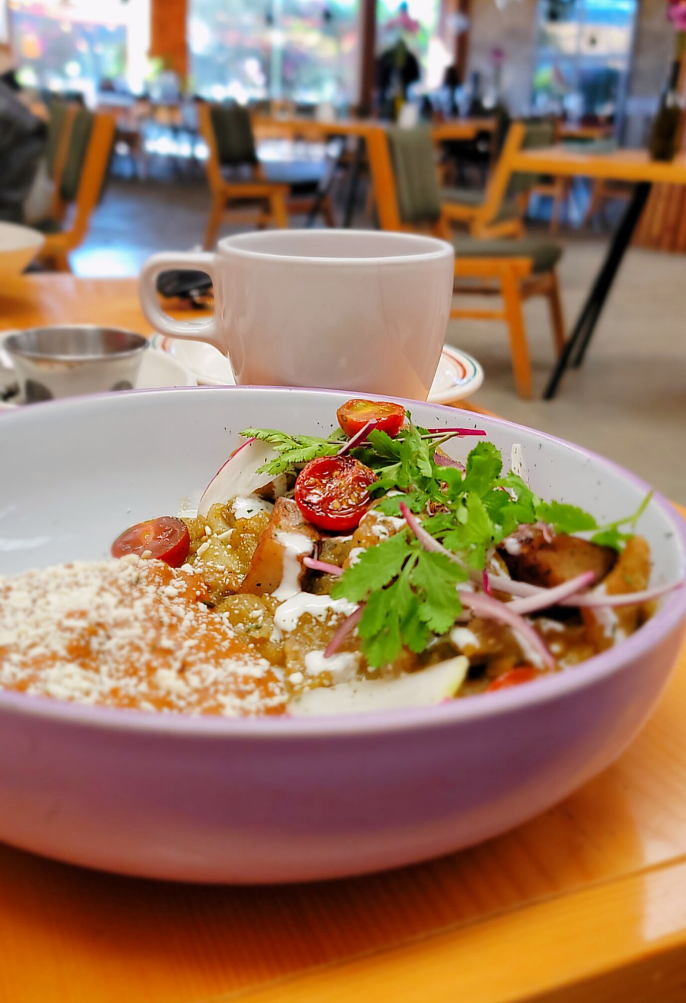Uma tigela de comida com uma xícara de café ao fundo.