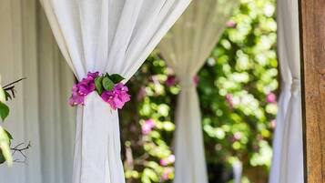 Um corredor com cortinas brancas e um detalhe floral no final.