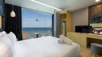 Quarto de hotel moderno com uma cama grande, uma escrivaninha, uma televisão e vista para o oceano.