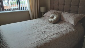 Cama bem arrumada com colcha estampada e uma almofada decorativa.