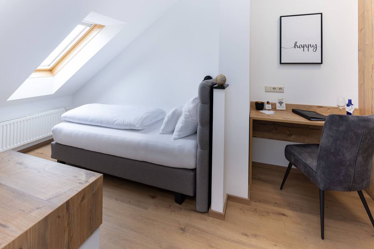 Quarto loft moderno com claraboia, cama, escrivaninha e cadeira.