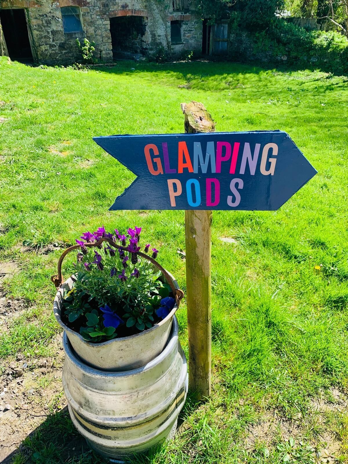 Placa indicativa para as Cabanas Glamping, com um vaso de planta ao lado.