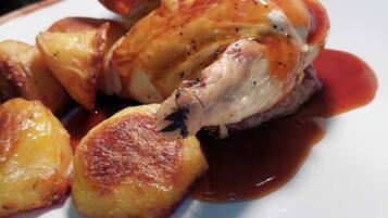 Um prato com frango assado, batatas e molho.