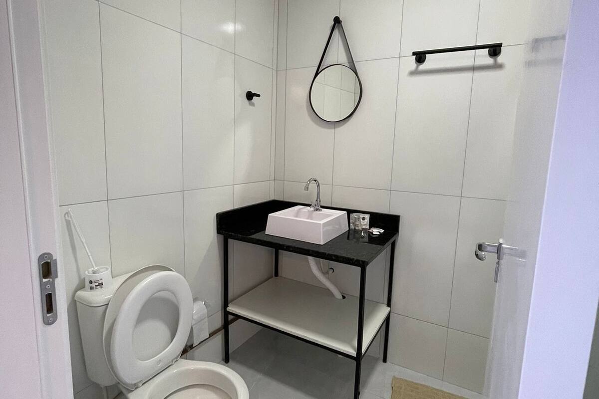Uma casa de banho pequena e moderna com sanita, lavatório e espelho.