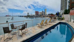 Piscina com espreguiçadeiras e vista para o calhavec e o horizonte da cidade.
