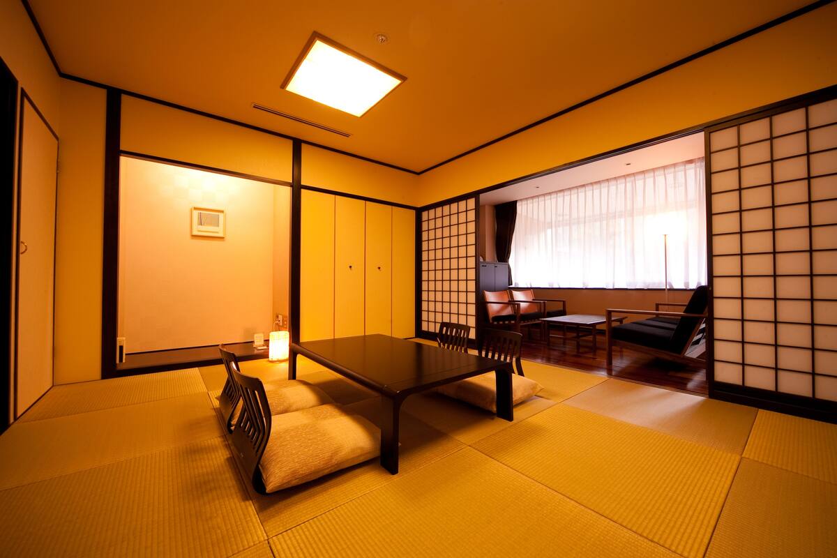 Um quarto japonês tradicional com tatames, uma mesa baixa e portas deslizantes.
