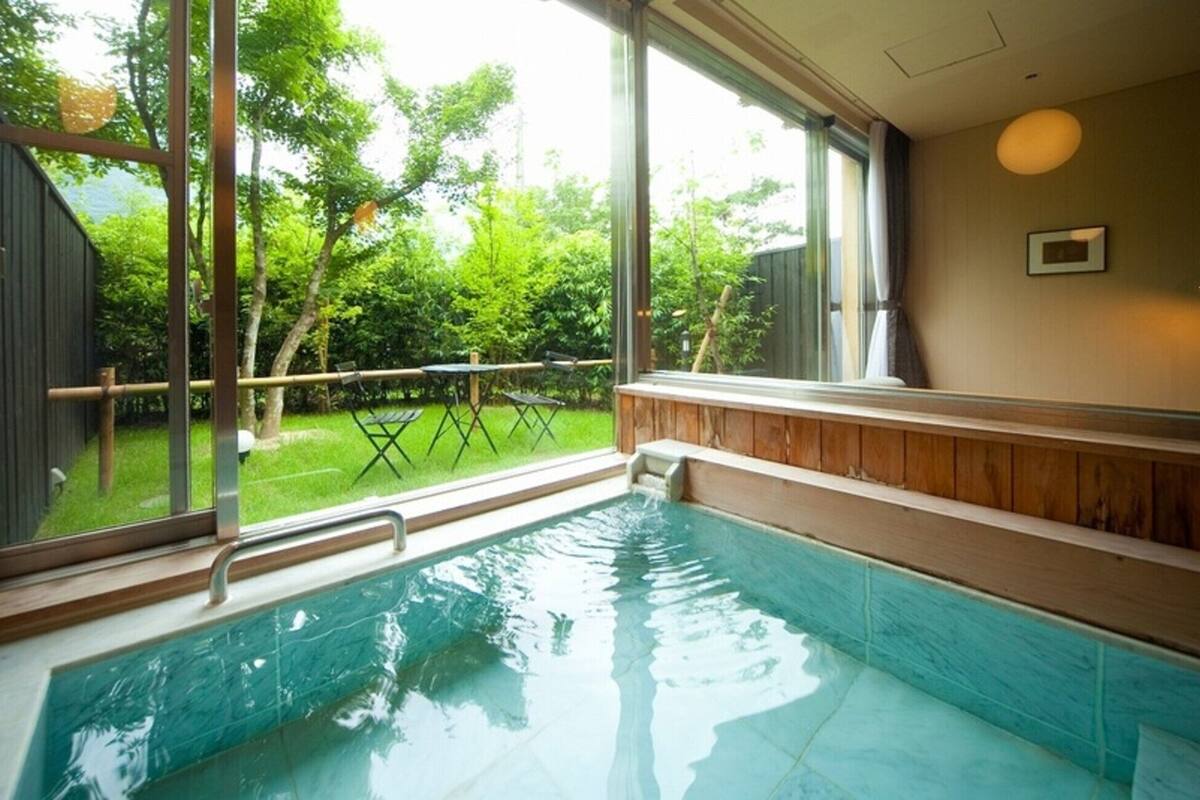 Uma banheira de hidromassagem com vista para um gramado e árvores.