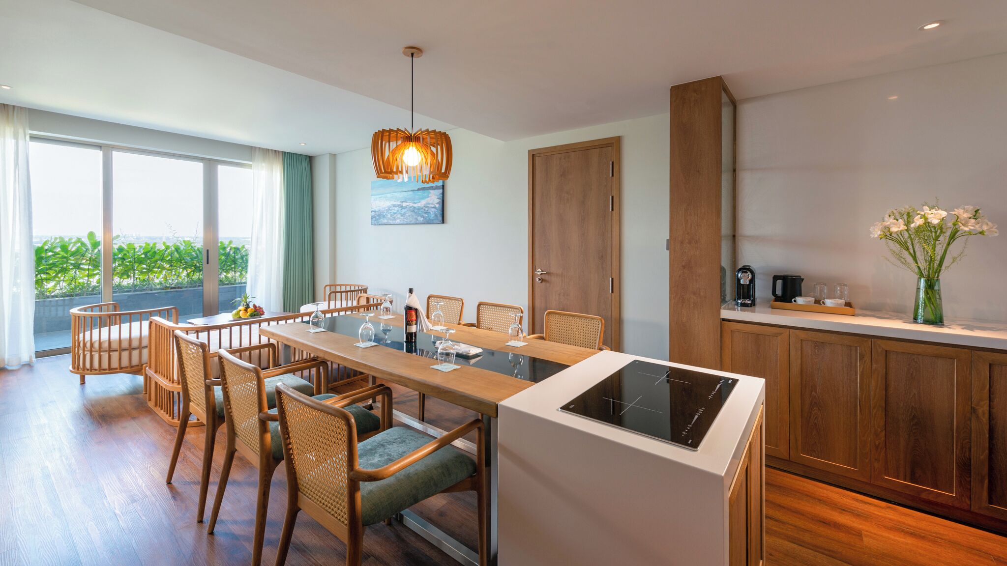 Uma cozinha moderna com ilha central, armários de madeira e um espaço de jantar com cadeiras de vime.