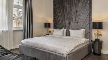 Quarto moderno com uma cama grande, cortinas escuras e duas luminárias de cabeceira.