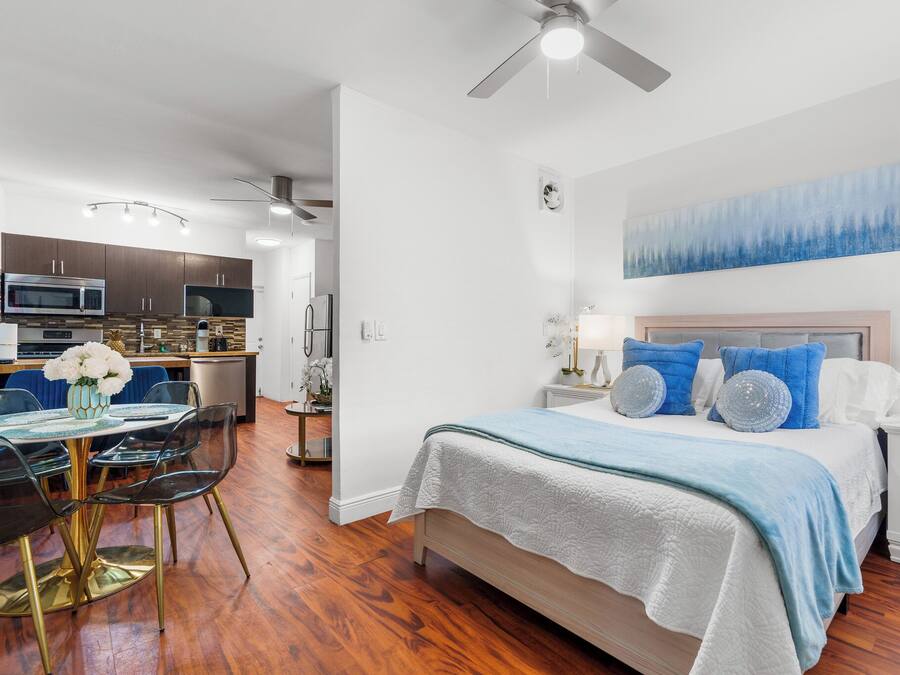 Quarto moderno com uma cama grande, mesas de cabeceira e vista para a área da cozinha.