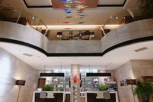 Um hall de hotel moderno com teto curvo, uma coluna central e uma escadaria.