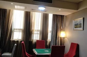 Quarto com uma mesa verde, cadeiras vermelhas, luminária e quadro pendurado na parede.