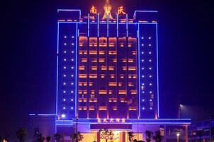 Hotel de vários andares com uma torre central e sinalização iluminada.