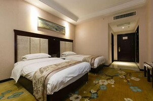 Quarto de hotel com duas camas, um quadro grande na parede e um tapete floral.