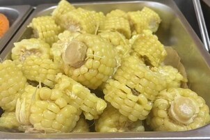 Uma travessa com espigas de milho cozidas em uma cozinha.