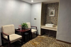 Quarto nos fundos com mesa de jantar, duas cadeiras, uma pequena planta e banheiro com azulejos no backsplash e pia.