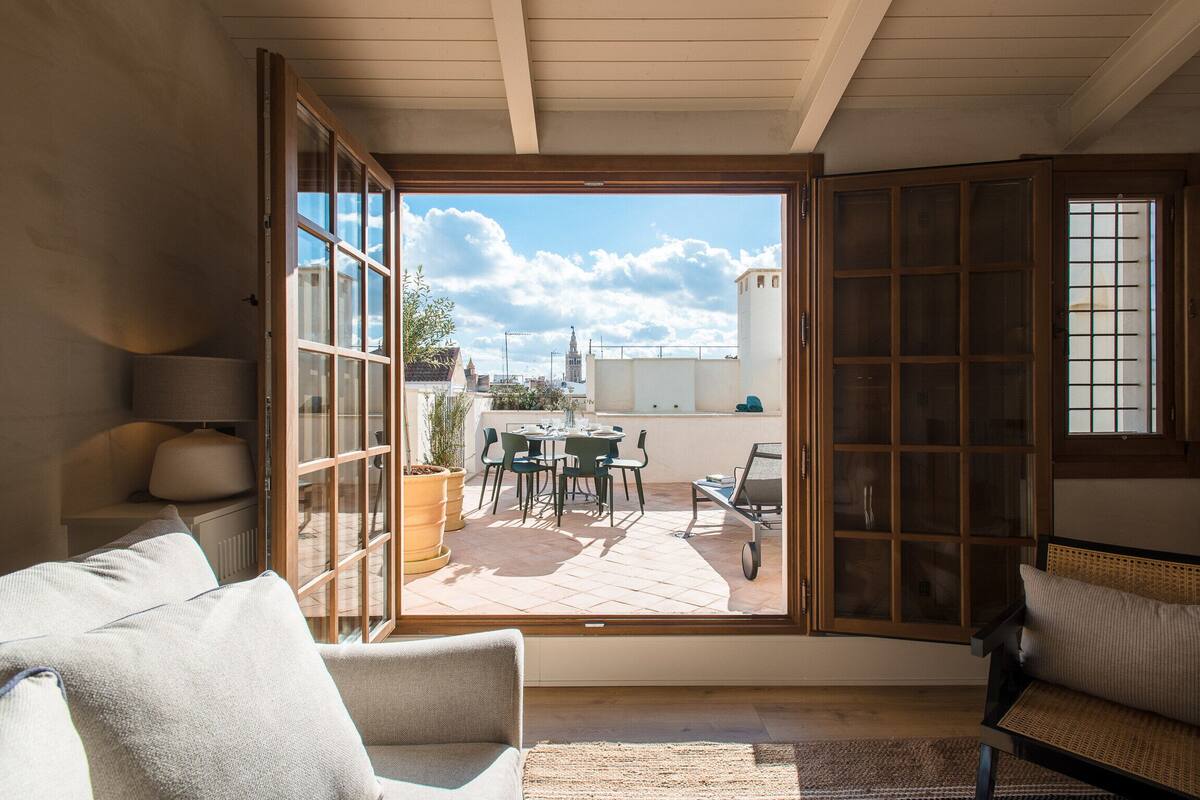 Quarto com porta de correr de vidro que dá para um pátio externo com mesa e cadeiras.