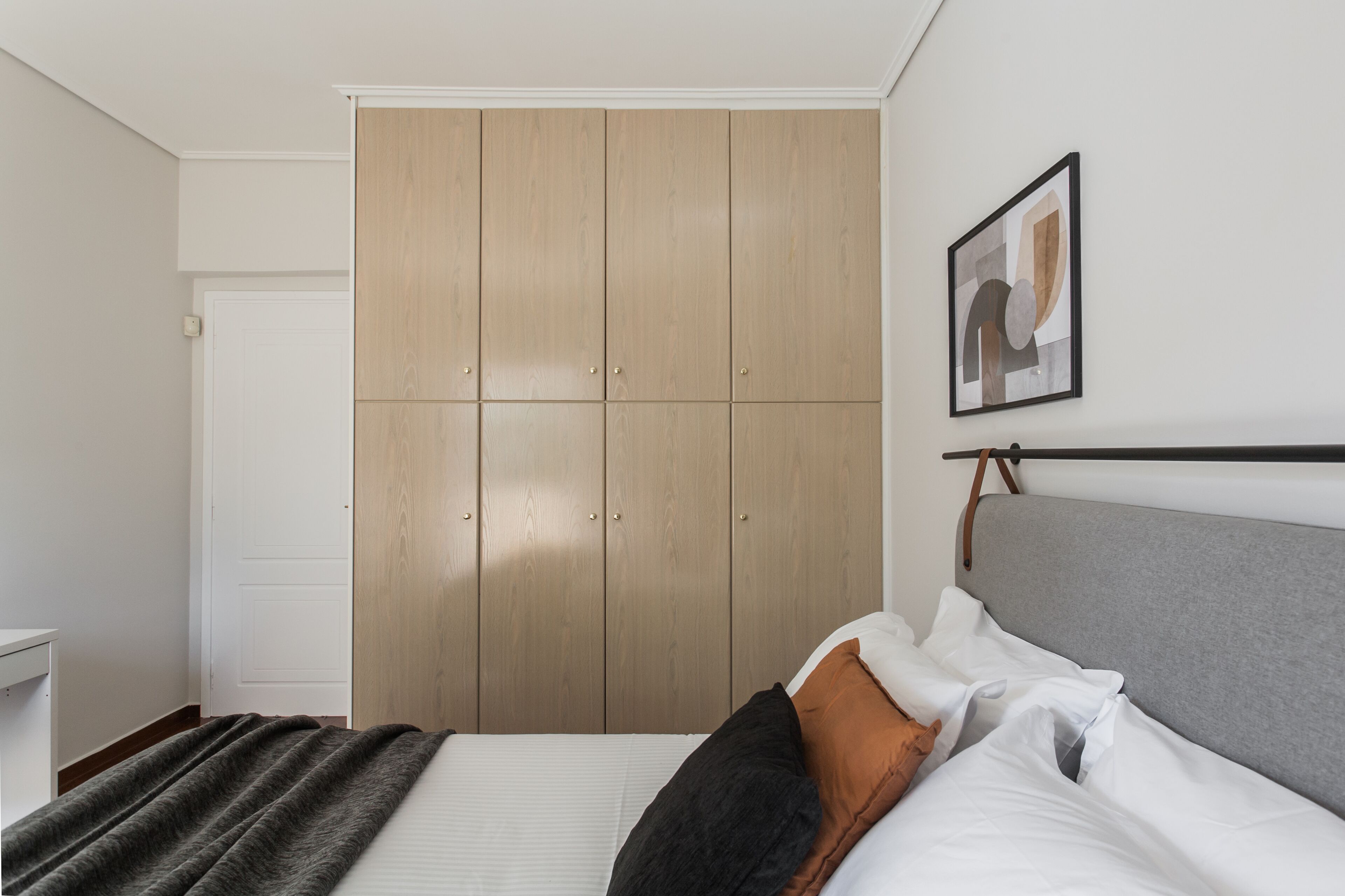 Quarto com cama, guarda-roupa e quadro na parede.