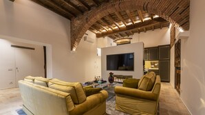 Uma sala de estar espaçosa com teto alto, TV de tela plana e lareira moderna.