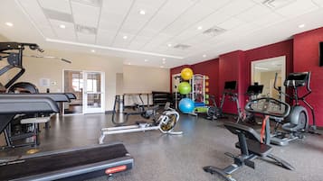 Uma academia com esteiras, elípticos e bolas de exercício.