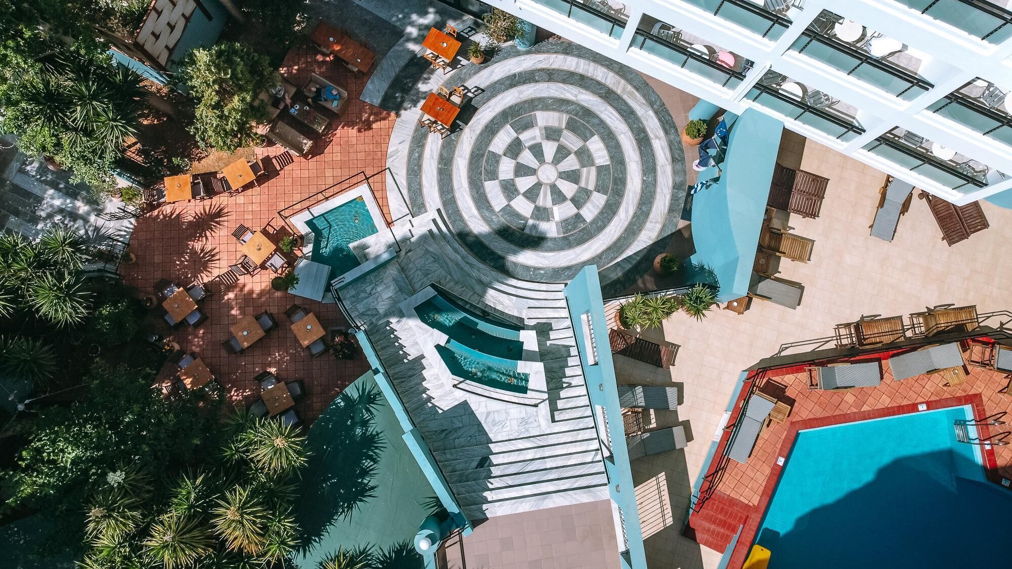 Vista aérea de um hotel com um pátio circular central, áreas de estar ao ar livre e uma piscina.