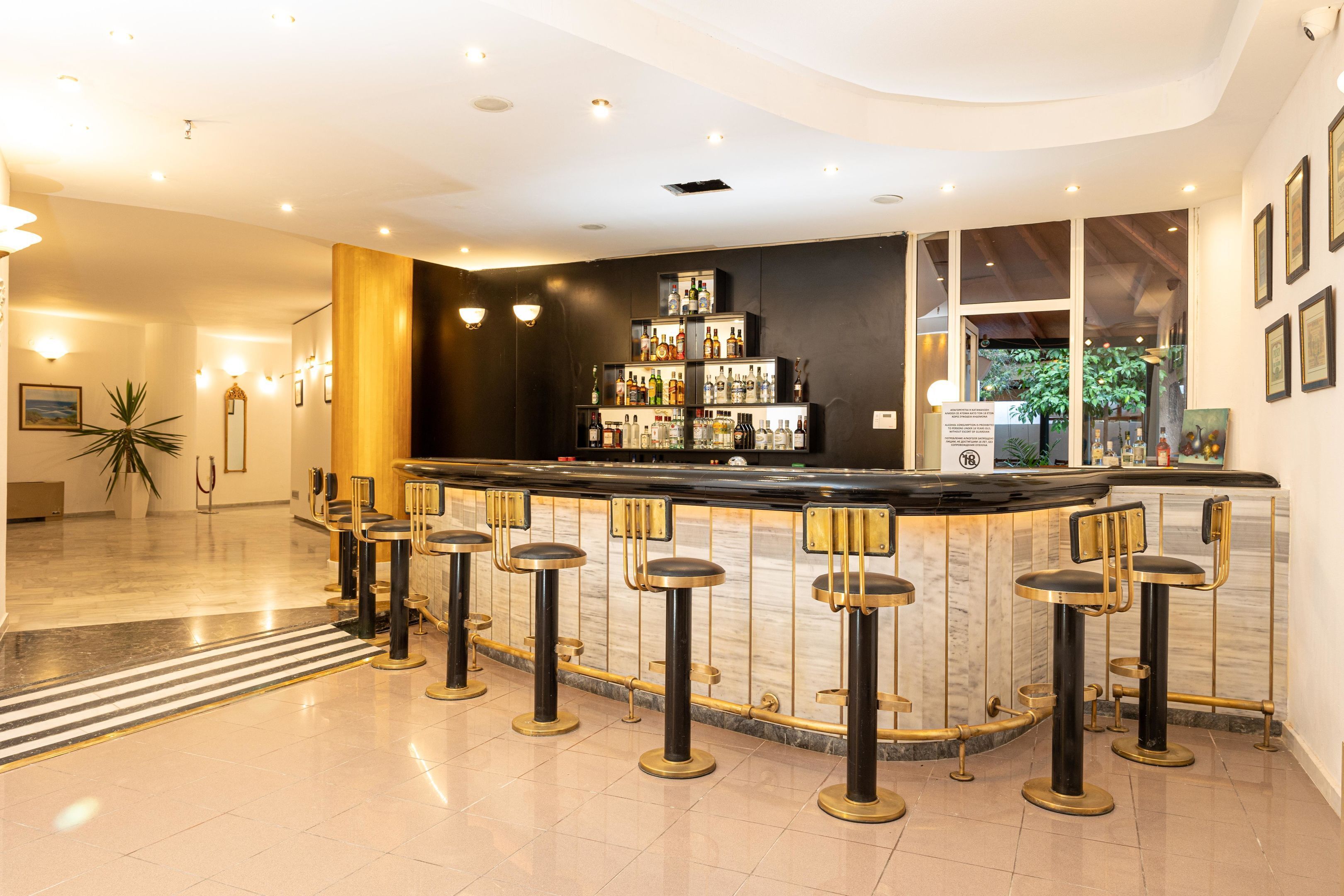 Uma área de bar moderna com balcão curvo, vários banquinhos e uma variedade de garrafas expostas.