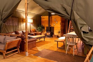 Acolhimento em tenda aconchegante, com interior de madeira, sofá, mesa e lareira.