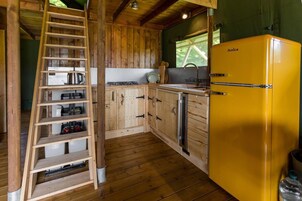 Uma cozinha com armários de madeira, uma geladeira amarela e uma escada de madeira.
