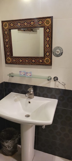 Um banheiro com pia branca, um espelho decorativo com moldura floral e azulejos estampados nas paredes.