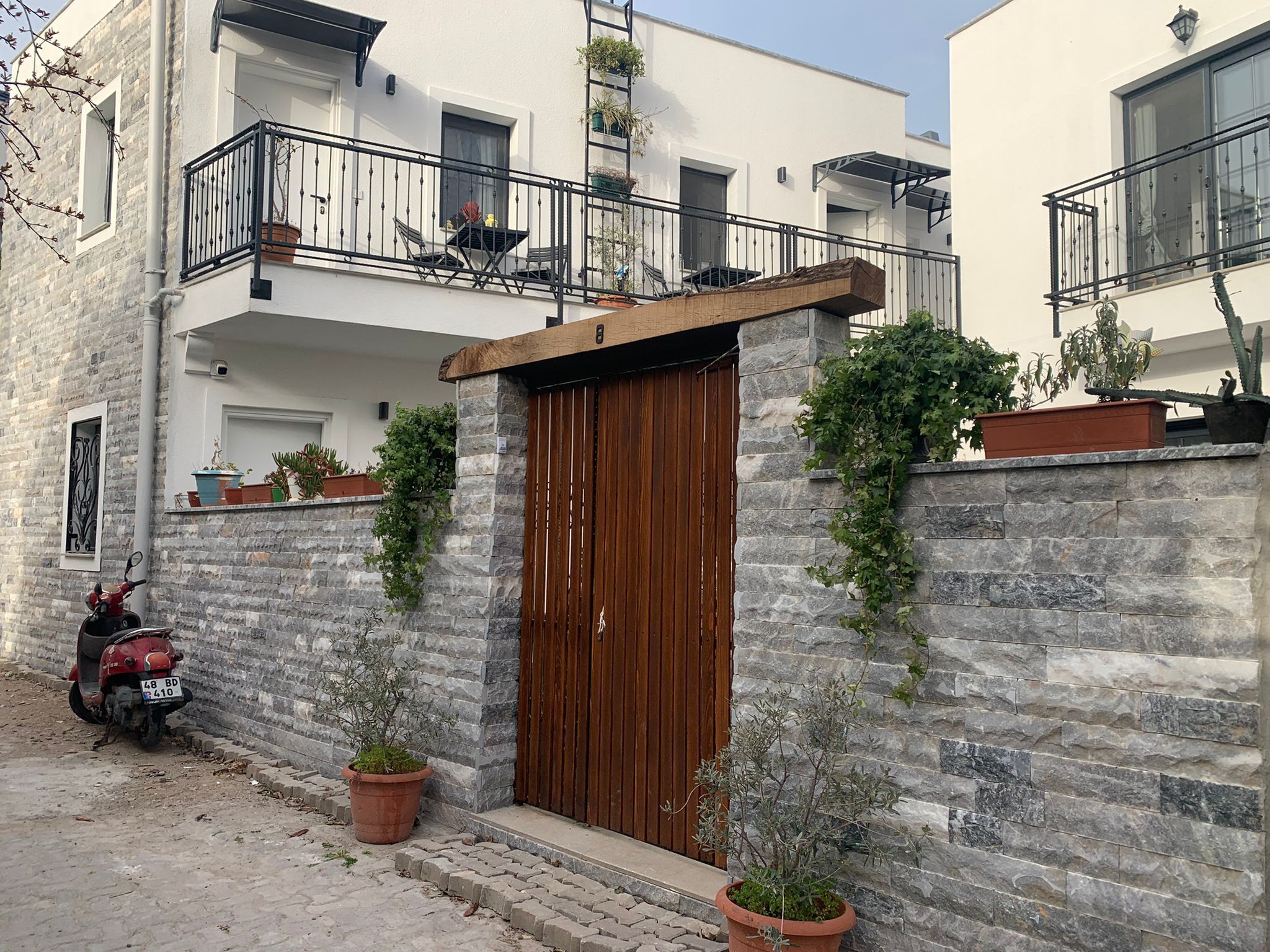Um edifício residencial com fachada de pedra, porta de madeira e varanda com mobiliário exterior.