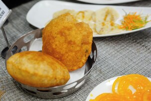 Dois alimentos fritos numa bandeja de metal, um prato com salada e um prato com molho amarelo.