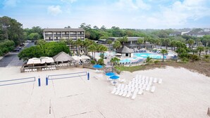 Um resort com área de praia, piscina e um edifício com vários andares.