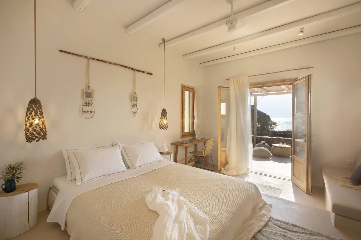 Quarto com cama grande, mesas de cabeceira, escrivaninha e vista para o exterior.