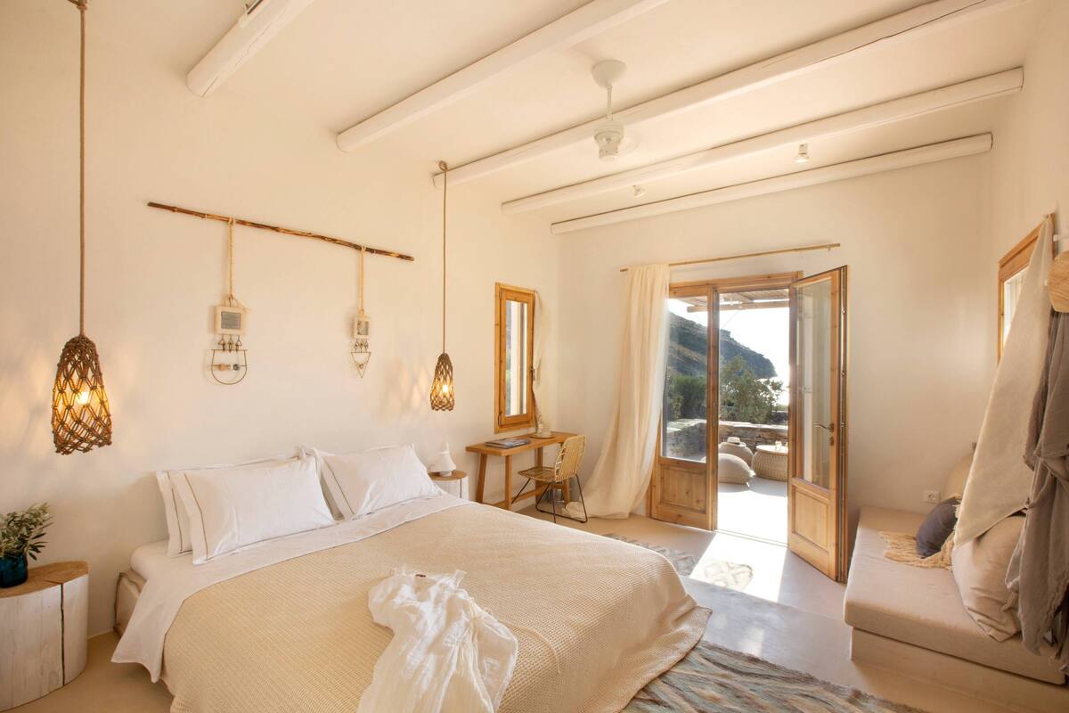 Quarto com uma cama grande, uma escrivaninha, uma cadeira e vista para o exterior.