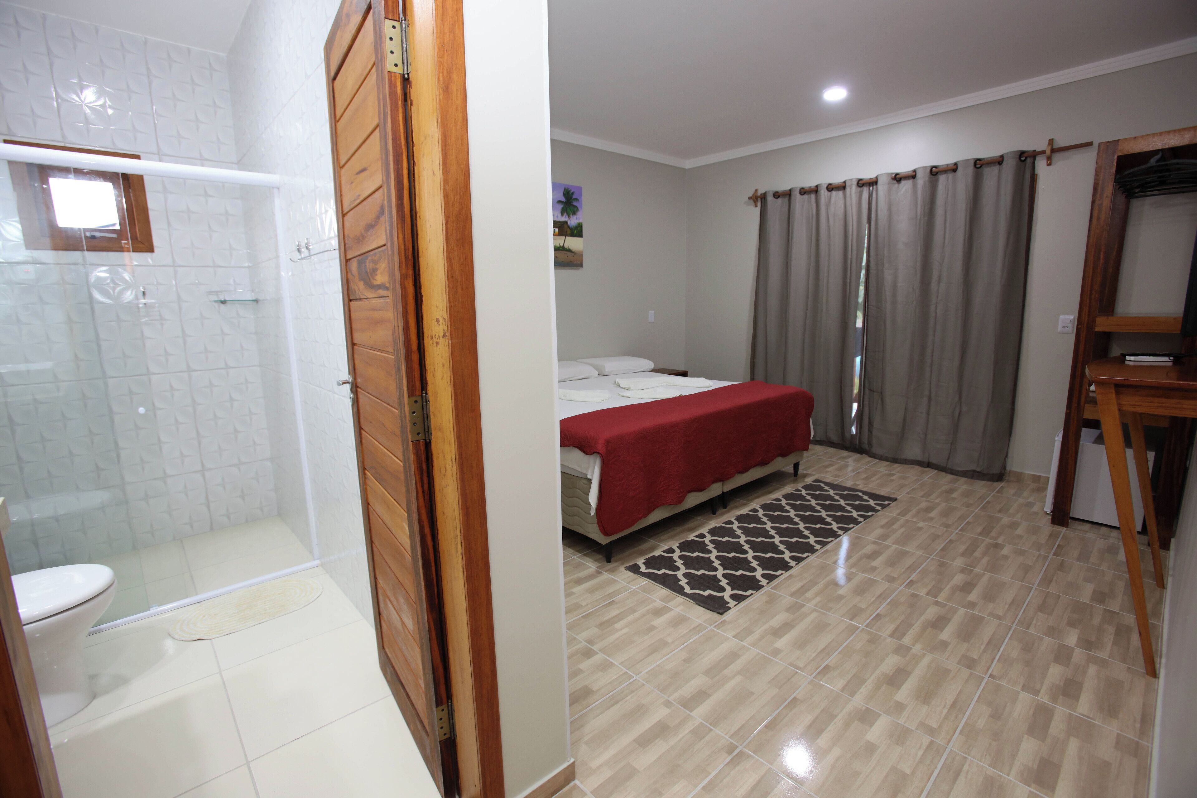 Quarto com uma cama, chuveiro e porta de madeira.