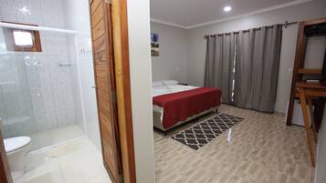 Quarto com uma cama, chuveiro e porta de madeira.