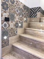 Escadaria com parede de azulejos estampados e um interruptor de luz.