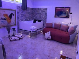 Um banheiro moderno com uma banheira branca, um sofá vermelho e uma pintura decorativa de um pássaro.