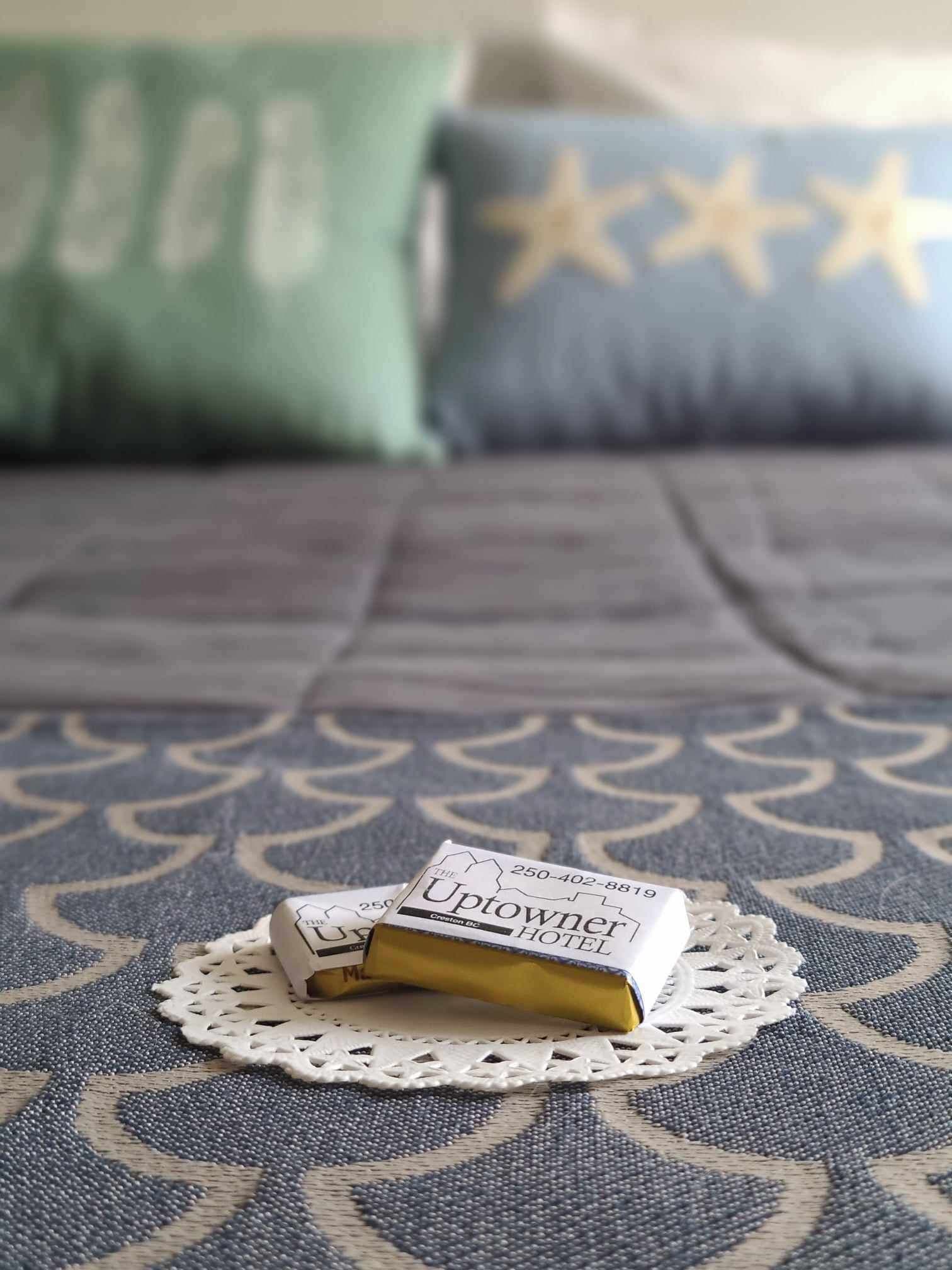 Quarto de hotel com um sofá estampado, um jogo de crochê e um travesseiro com desenhos de estrelas.
