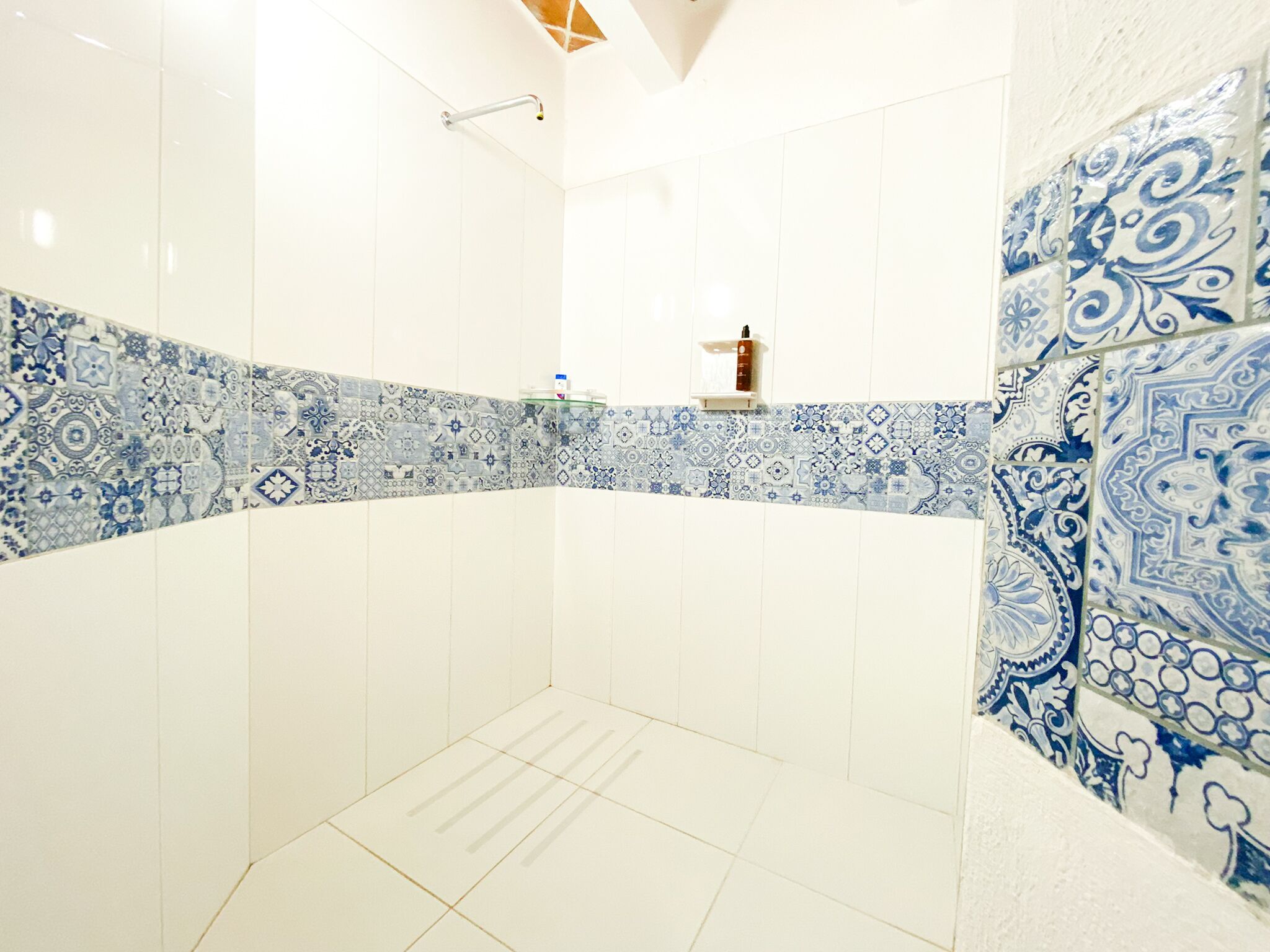 Casa de banho com azulejos brancos e azulejos decorativos azuis nas paredes.