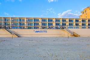 Edifício do Dolphin Beach Club com várias varandas e um primeiro plano arenoso.