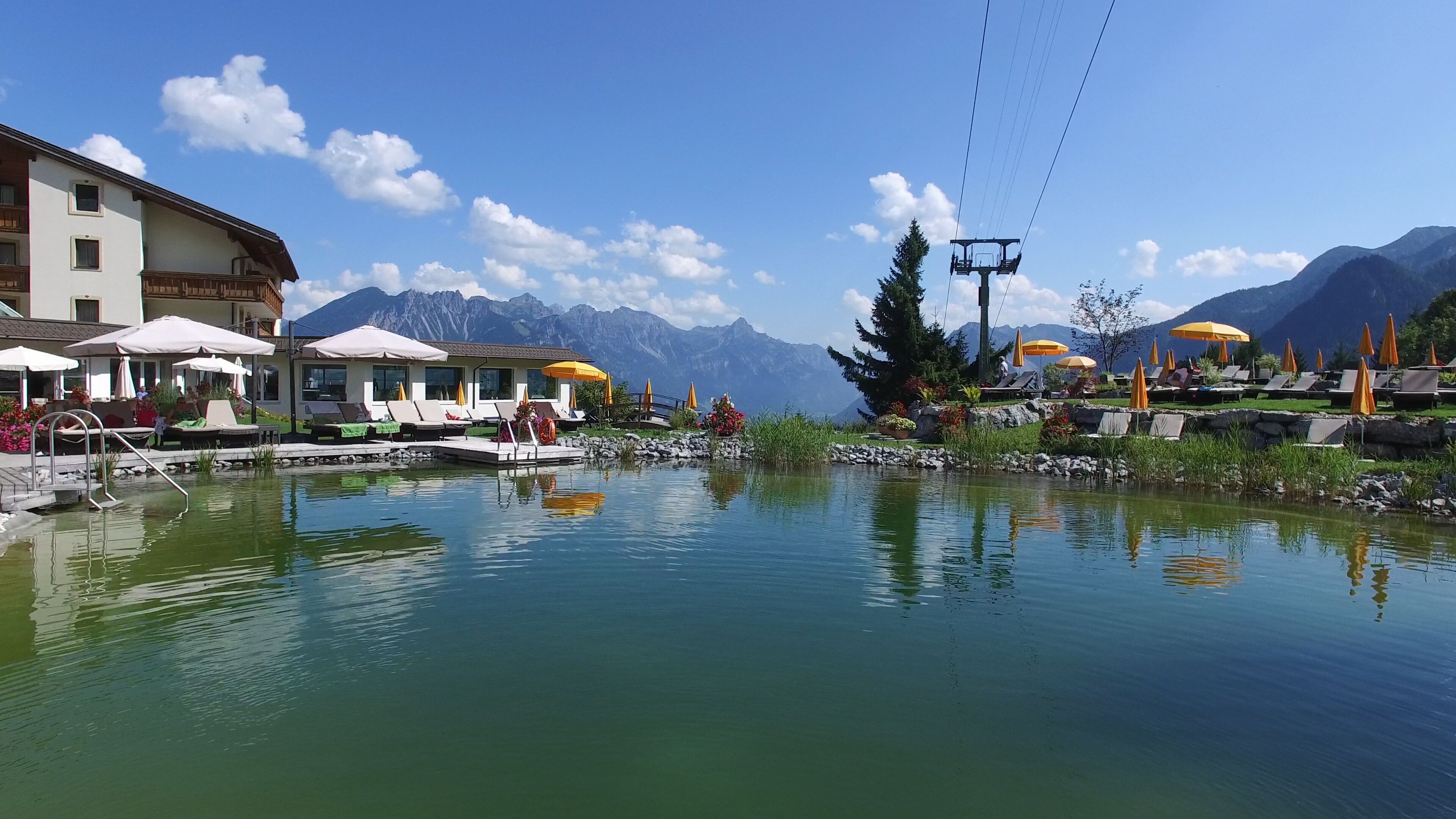 Hotel na beira do lago com área externa para sentar e vista para montanhas.