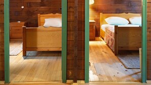 Uma cabana de madeira com duas camas de madeira, cada uma com estrutura verde, e um candeeiro pendente.