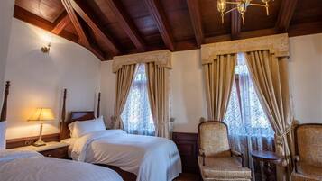Quarto de hotel com duas camas, um candelabro e uma cadeira.
