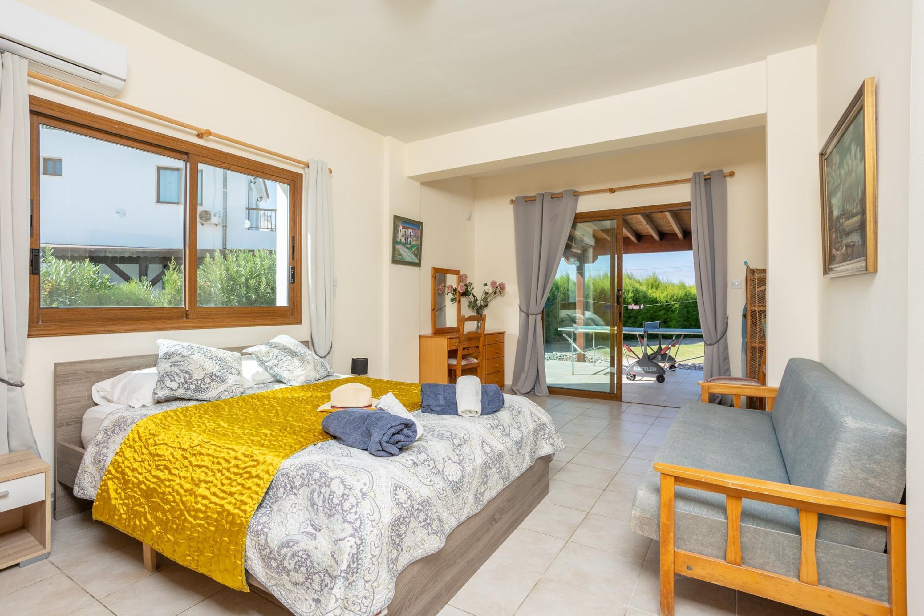 Quarto com cama, sofá, escrivaninha e janela com cortinas.