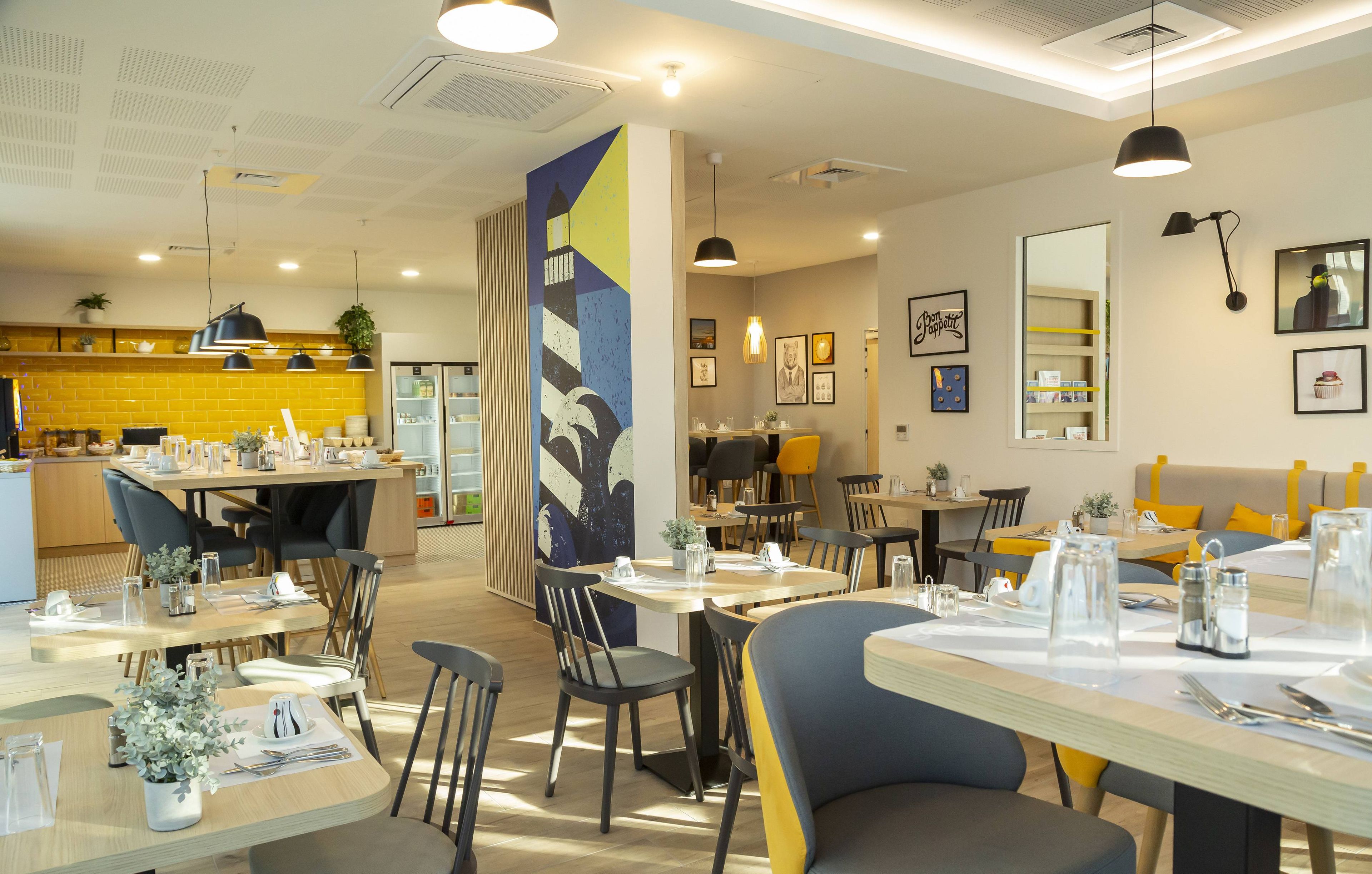 Interior moderno de restaurante com várias mesas, cadeiras e iluminação pendente.
