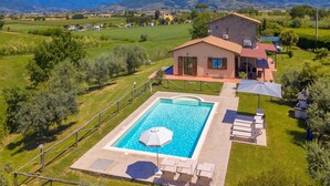 Uma casa com piscina, mobiliário de exterior e vista para o campo.