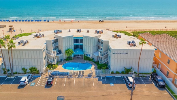 Hotel com piscina central, estacionamento e vista para a praia.