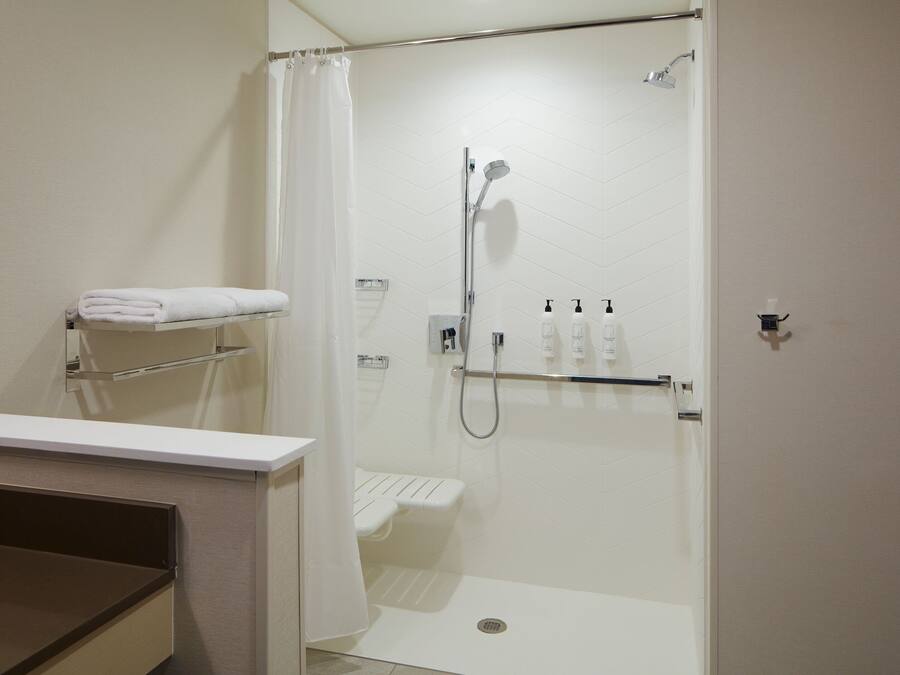 Uma casa de banho moderna com chuveiro, sanita e porta-toalhas.