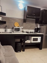 Cozinha compacta com torradeira, micro-ondas e fogão a gás.